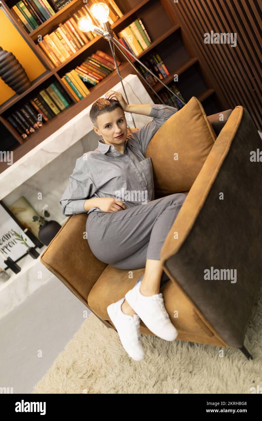 stylish caucasian adult woman lies in a chair in a cozy home ...