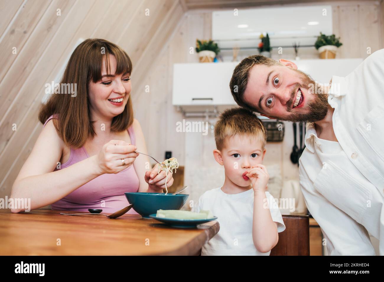 Very happy family eating pasta in the kitchen Stock Photo - Alamy
