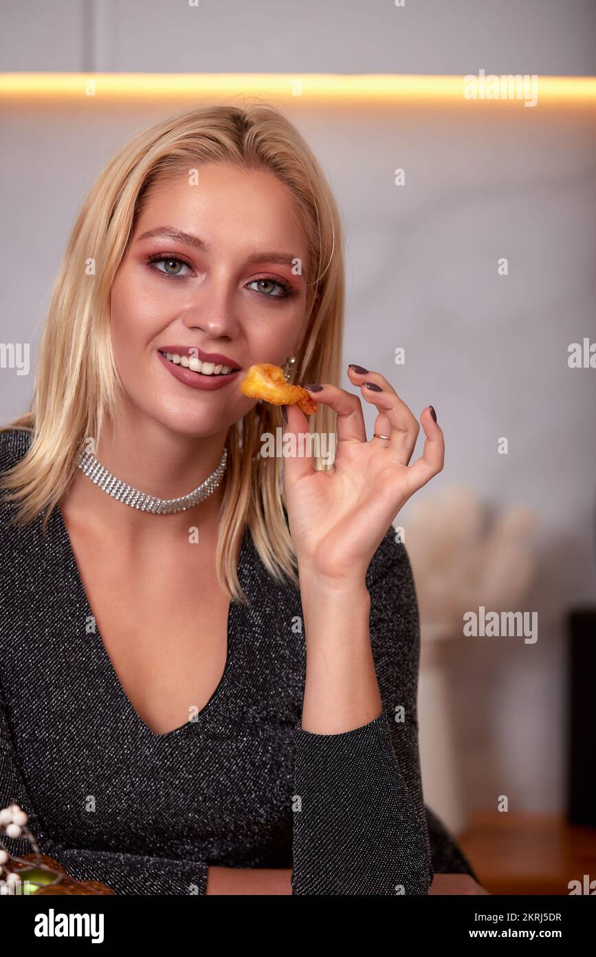 A woman with her hands eats a large appetizing shrimp. Selective focus ...