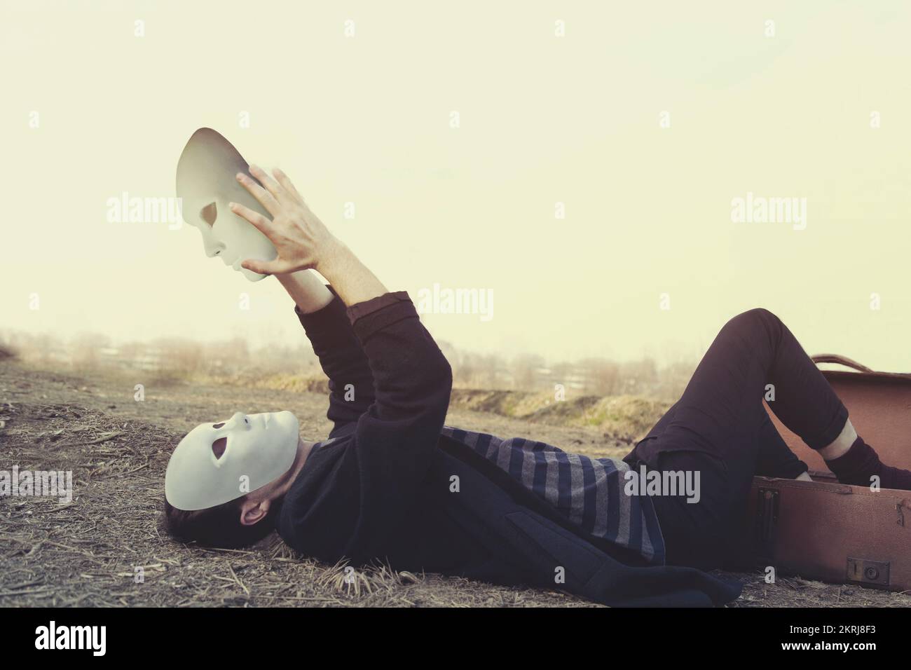 man with mask looks at another mask of herself, concept of ...