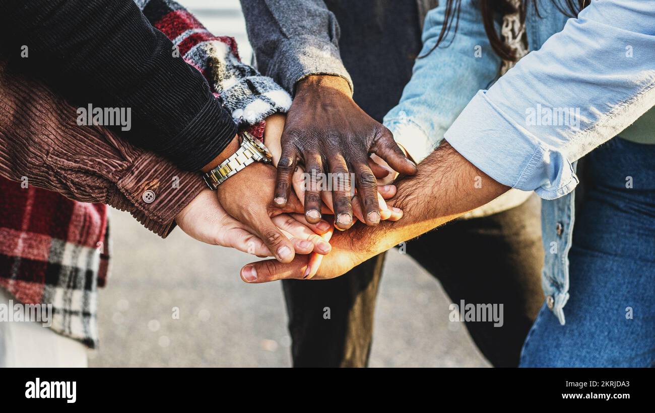 Diversity and teamwork as a group of diverse people joining hands as a ...