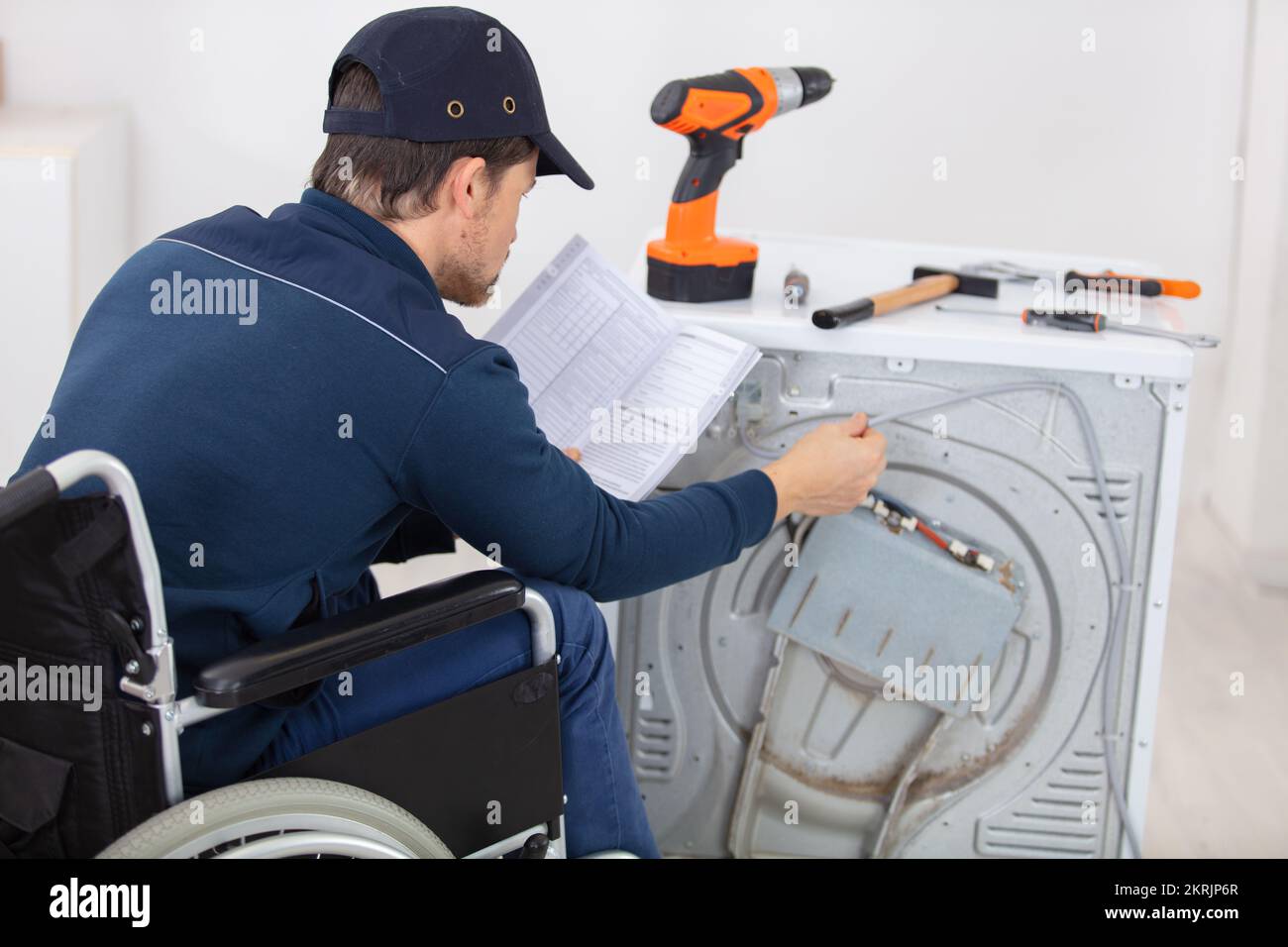 disabled repairman is repairing a washing machine Stock Photo - Alamy
