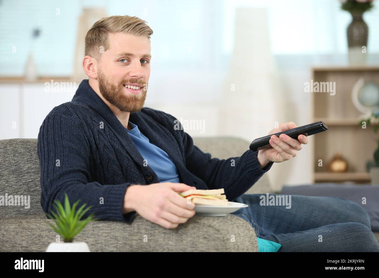 man changing tv channel with remote control while eating sandwich Stock ...
