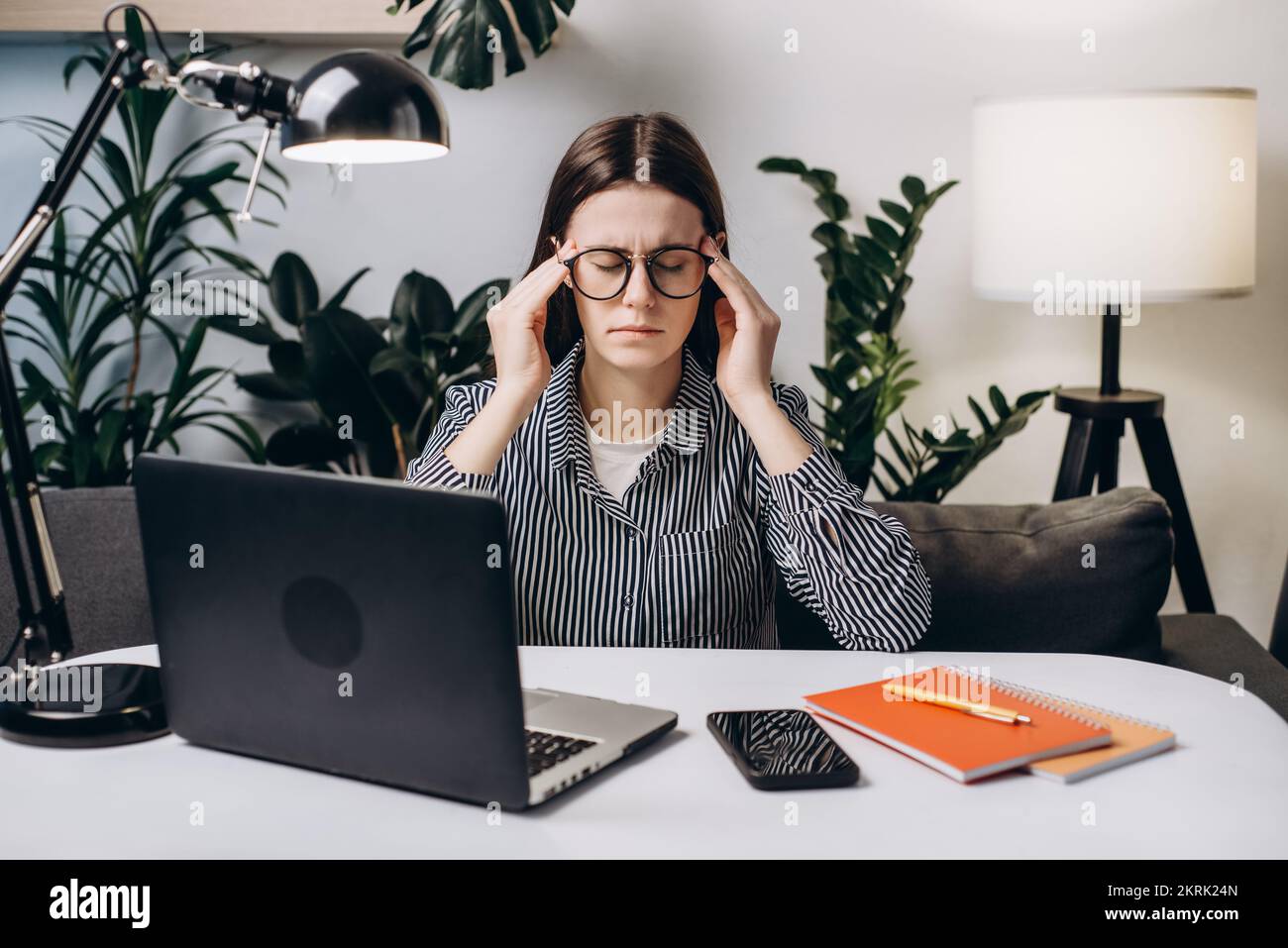 Tired young woman in eyeglasses with laptop sit on sofa suffer migraine ...