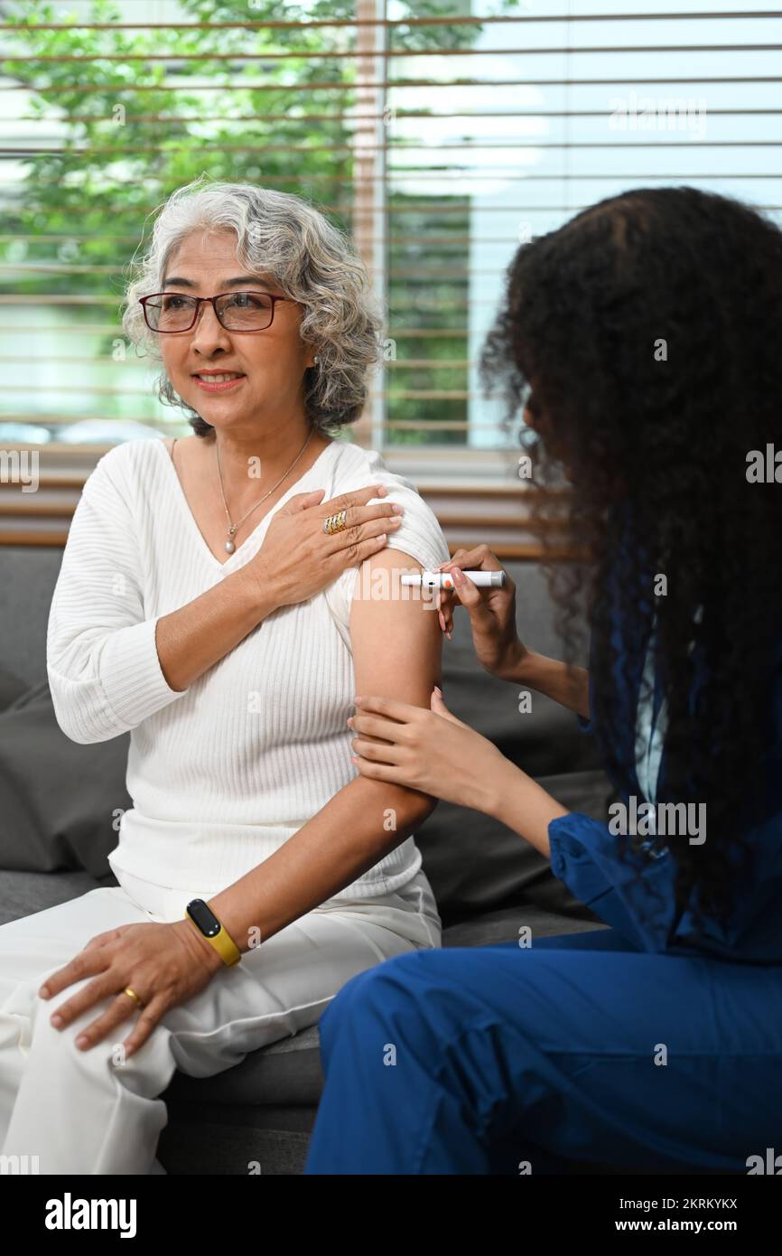 Practitioner nurse injecting insulin into diabetic senior female upper ...