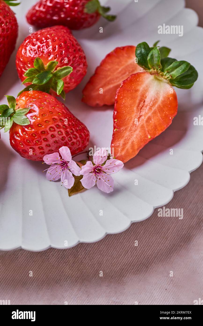 From above of fresh ripe whole and cut strawberries and gentle pink ...