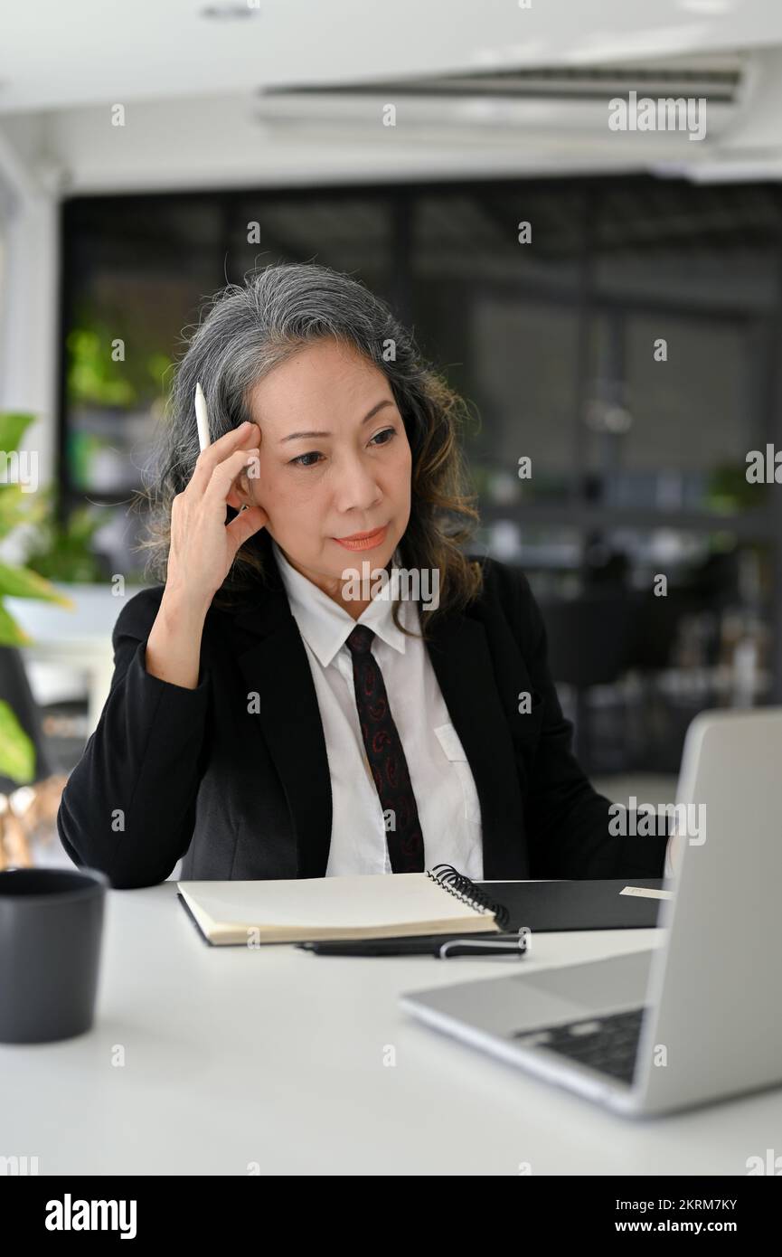 Portrait, Thoughtful Asian senior businesswoman or female executive ...