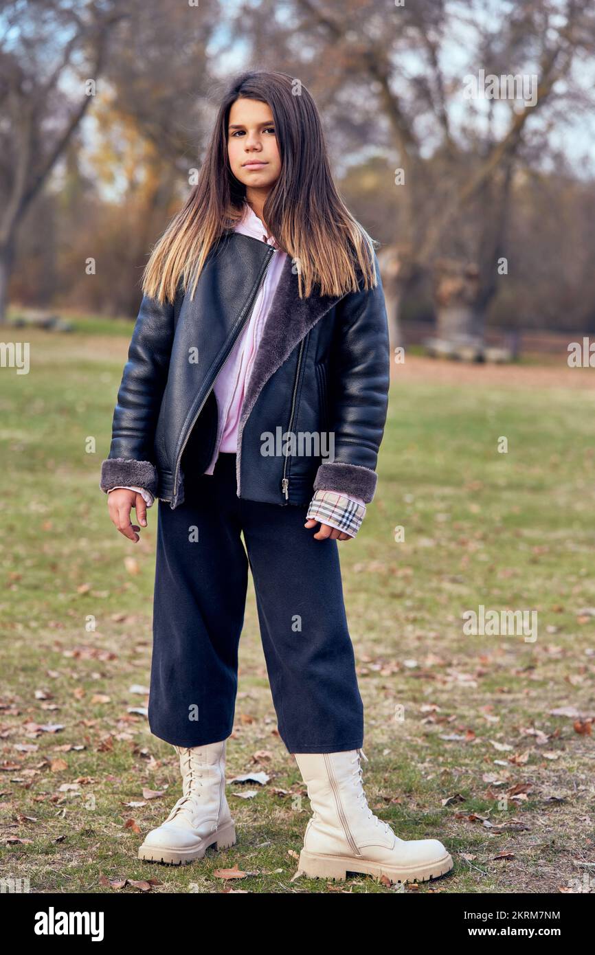 Full body of Hispanic teenager in warm outerwear standing looking at ...