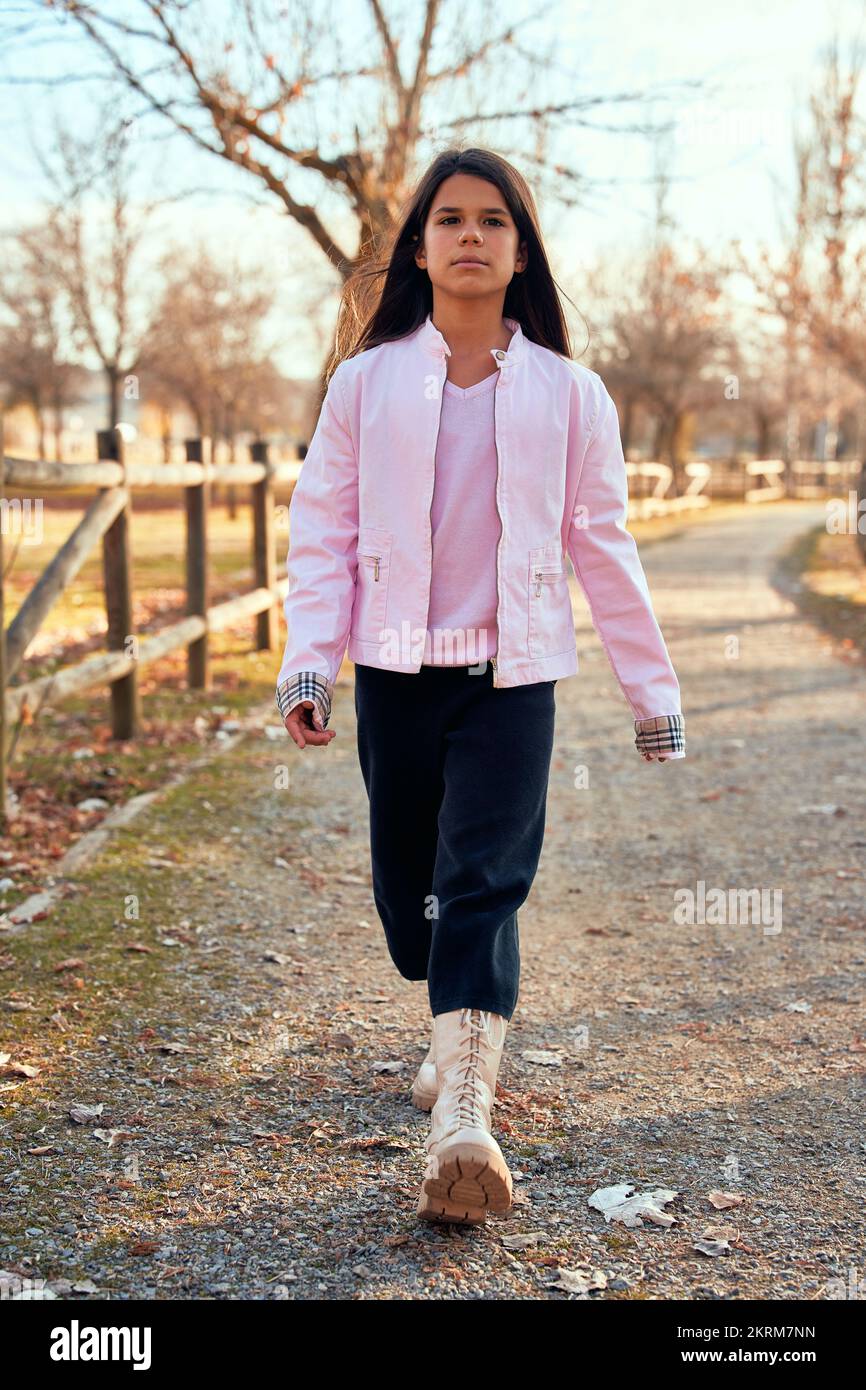 Full body of confident Hispanic teen girl in warm outfit strolling ...