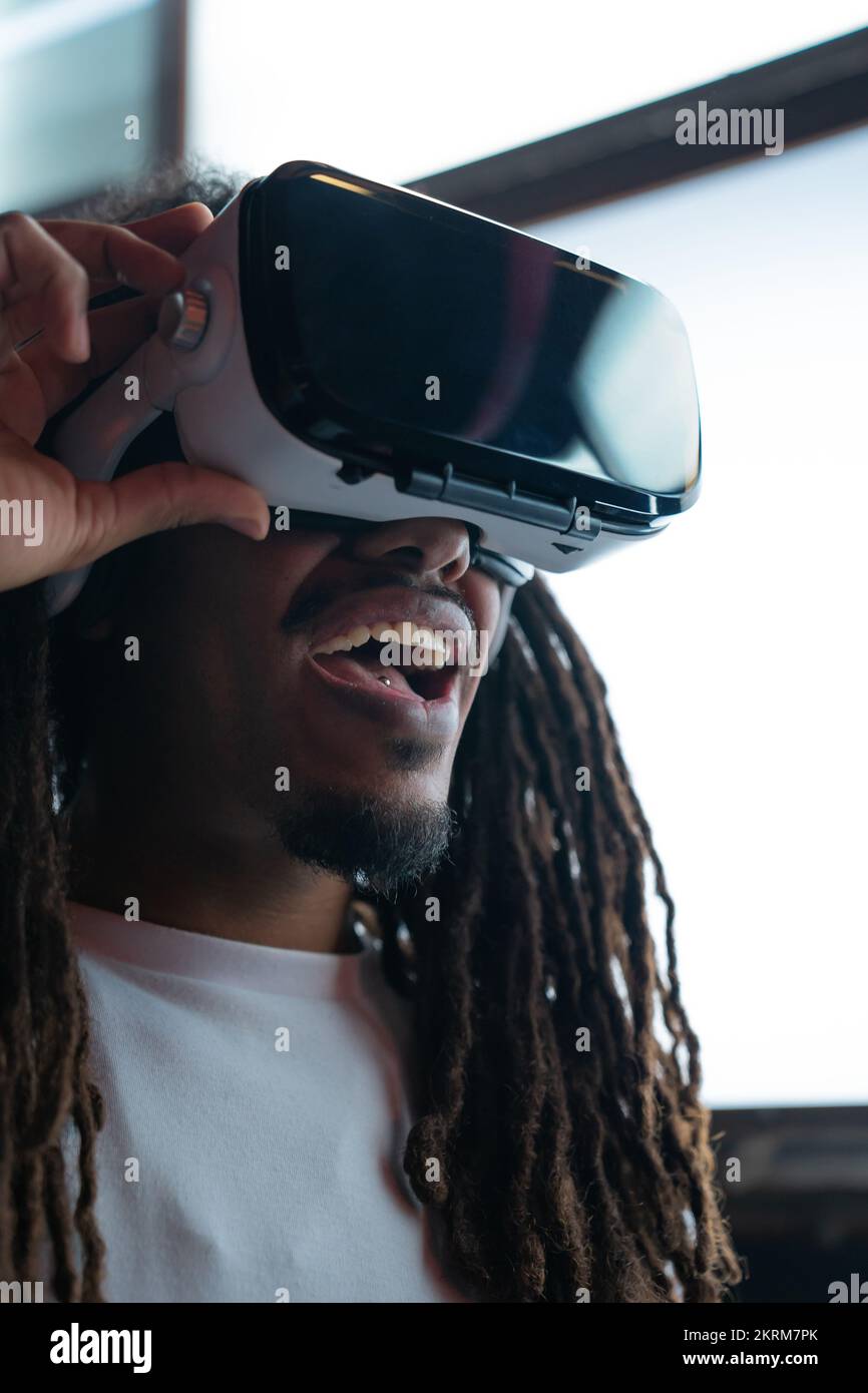 Young astonished African American male touching VR goggles experiencing ...