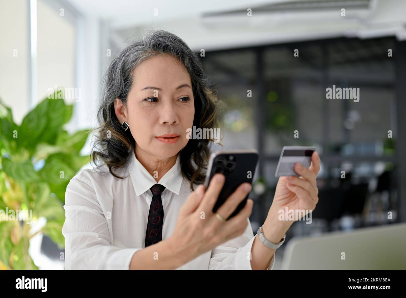 A beautiful Aged Asian businesswoman holding her smartphone and a ...