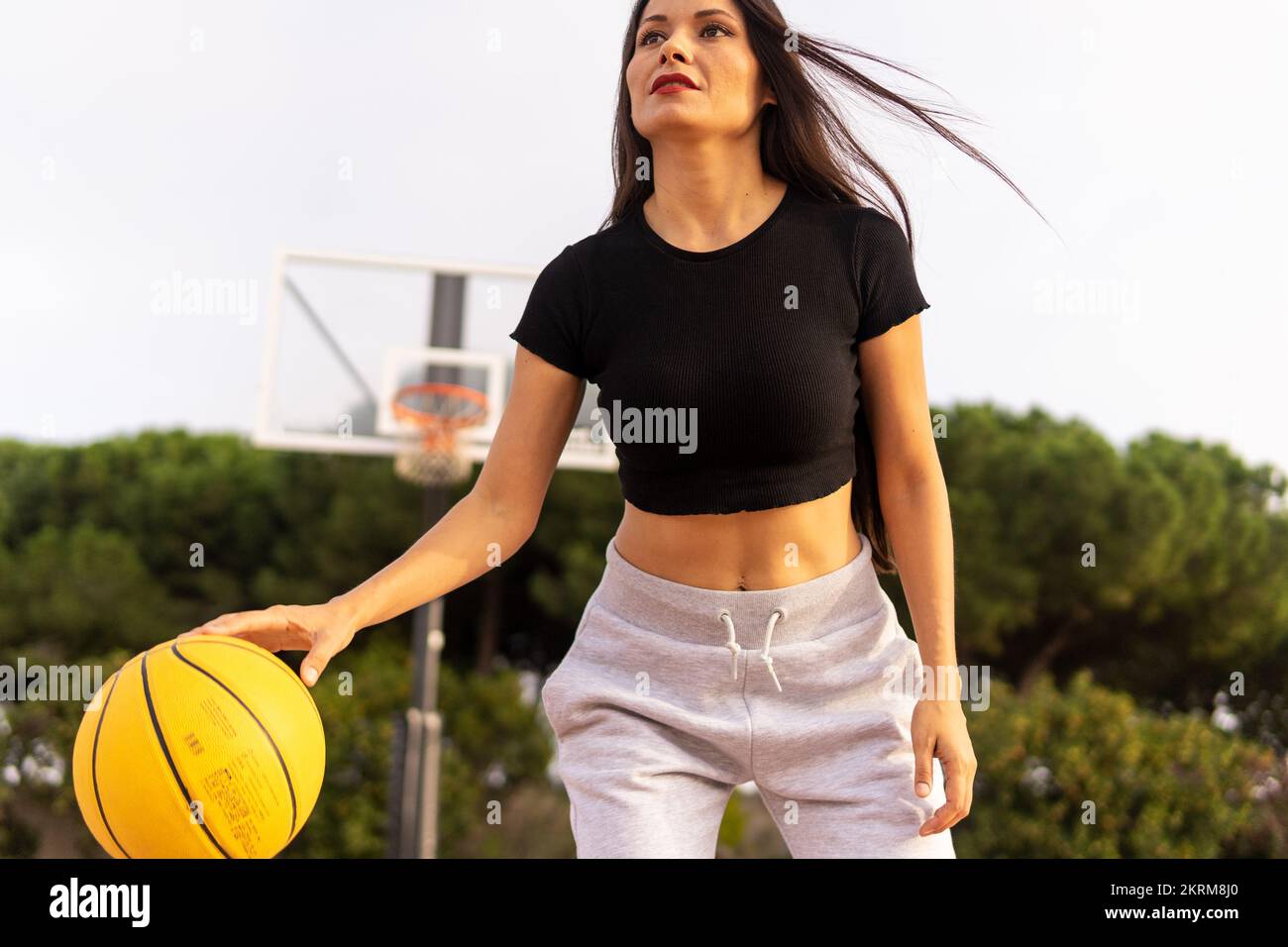 Low angle of crop fit female in activewear bouncing ball while training ...