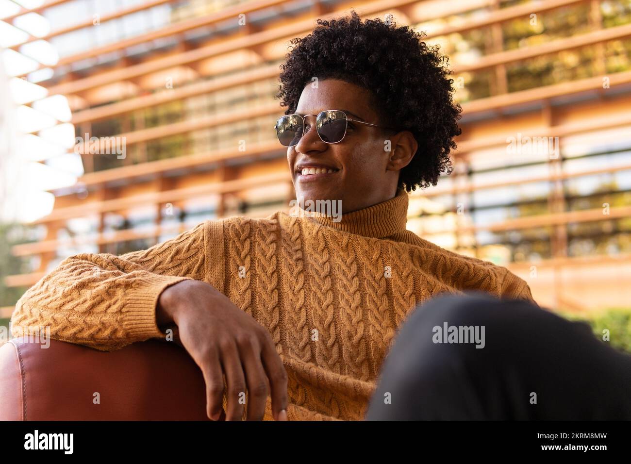 Trendy smiling African American male in knitted yellow sweater with ...
