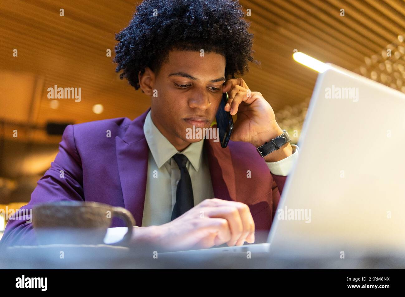 Low angle of concentrated young black male remote worker with dark Afro ...