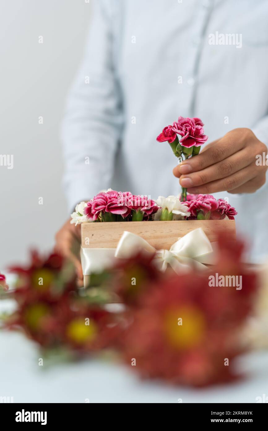 Crop anonymous female florist arranging pink and white carnations in ...