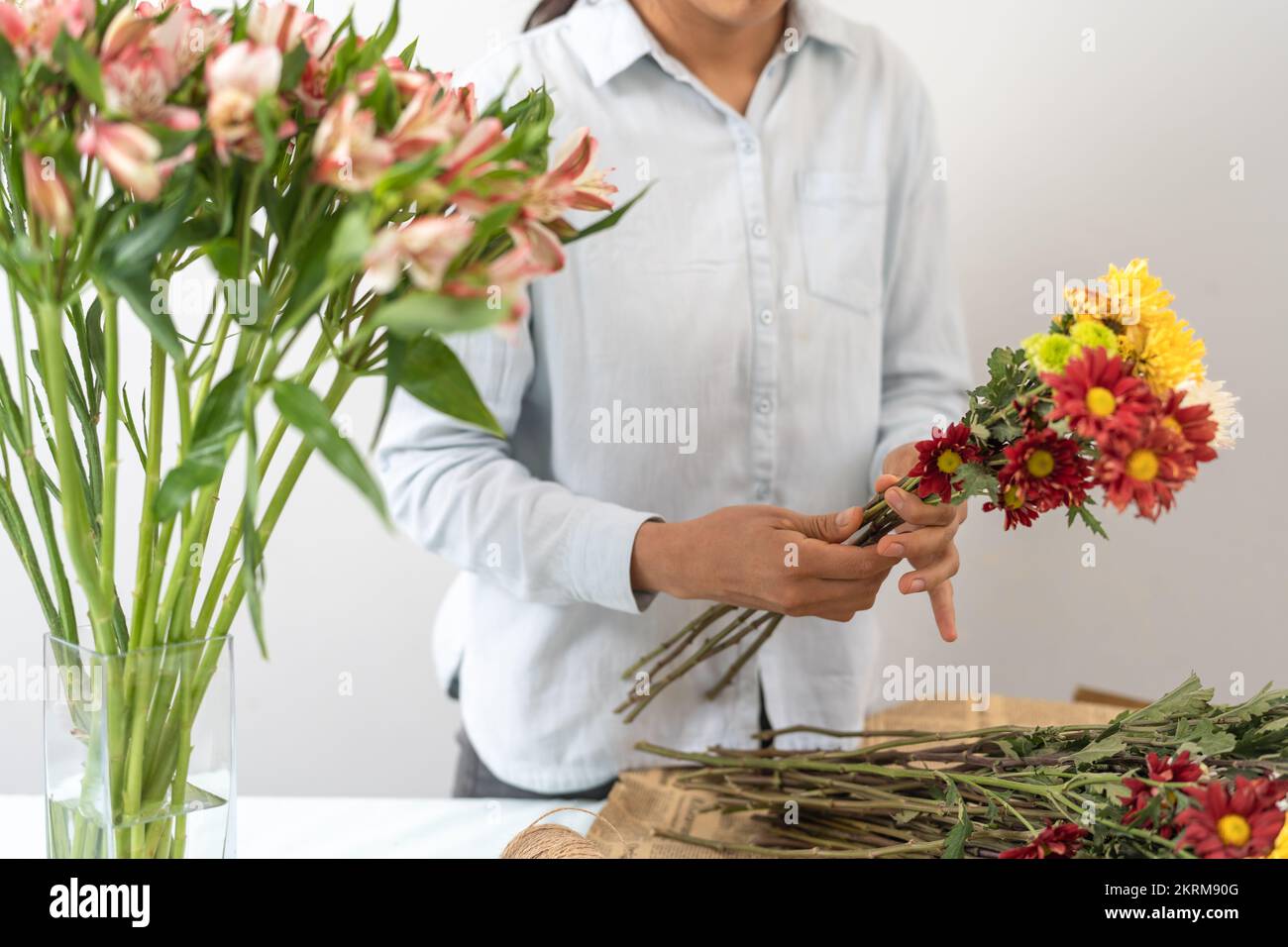 Cropped unrecognizable young female florist in white shirt standing ...
