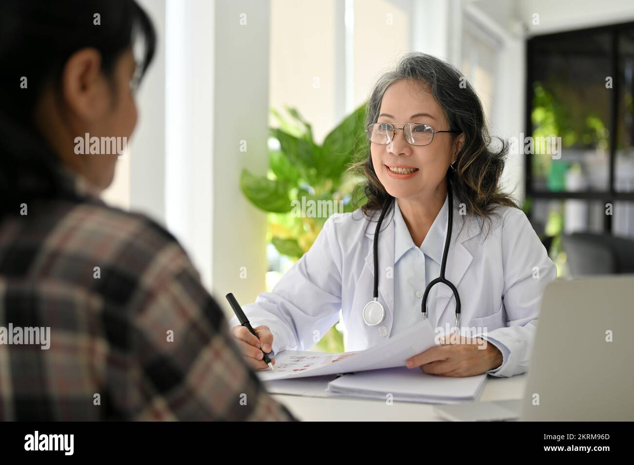 Happy and cheerful Asian aged female doctor having a nice conversation ...
