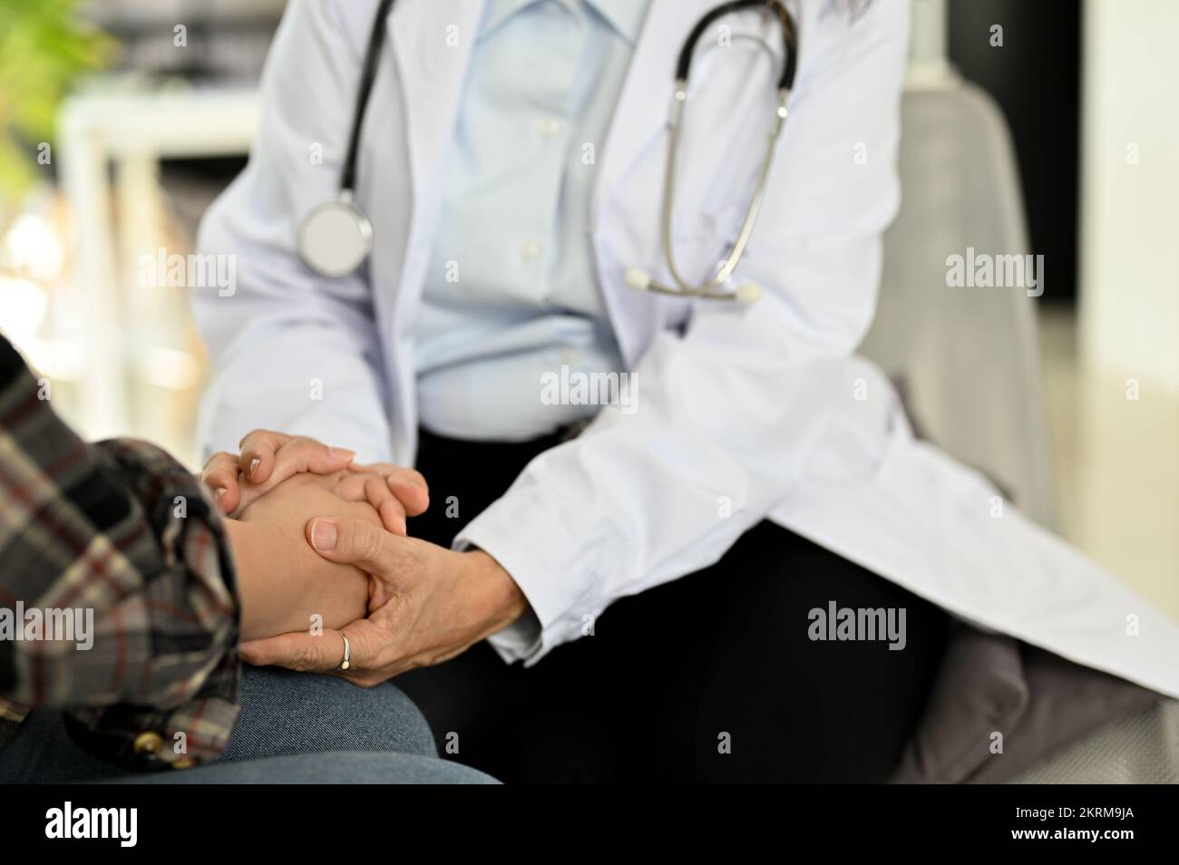 A professional Asian female doctor holding a patient's hands, giving ...