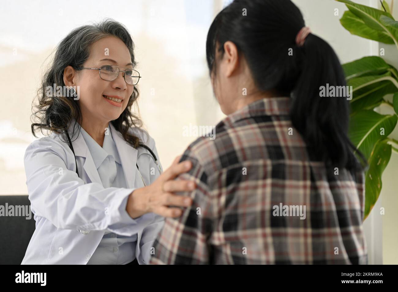 Professional And Peaceful Asian Senior Female Doctor Touches Her Young