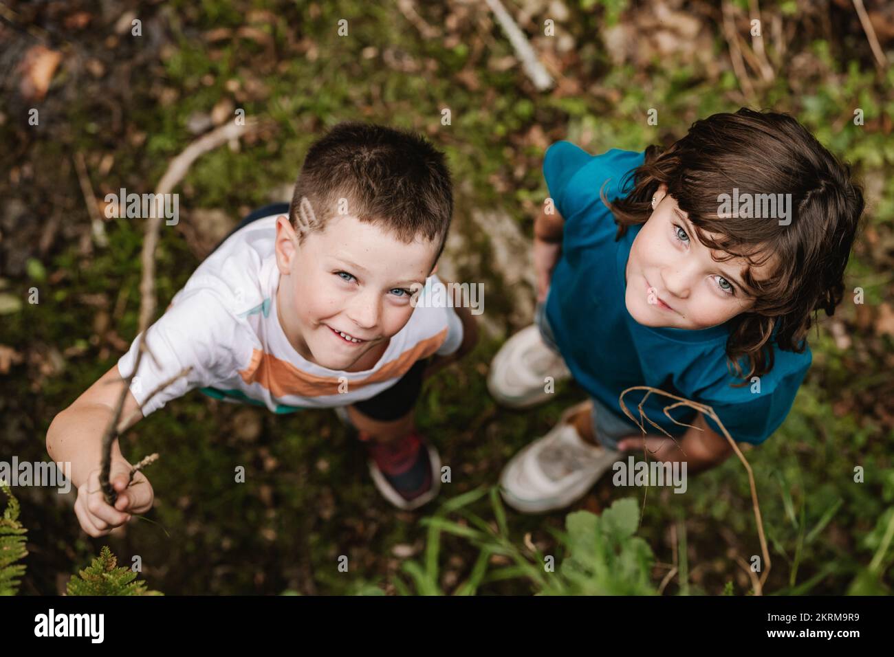 Top view of cheerful boy smiling and poking camera with stick while ...