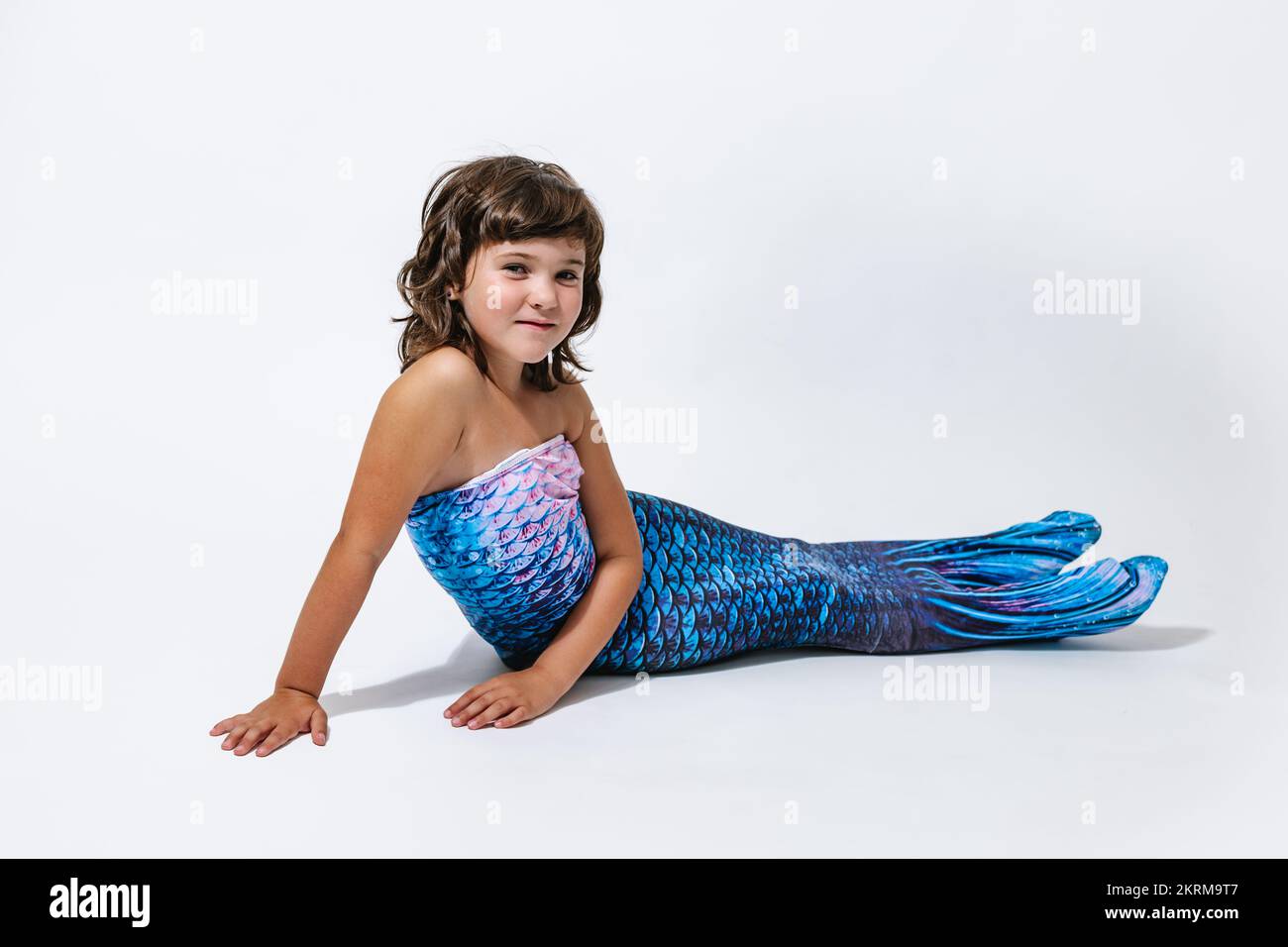 Full body of kid wearing blue mermaids tail looking at camera and ...