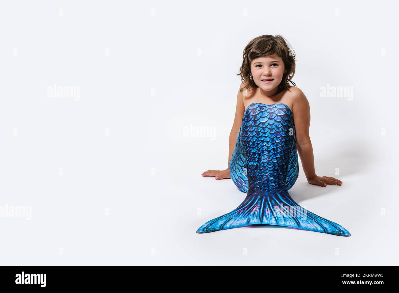 Full body of kid wearing blue mermaids tail looking at camera and ...