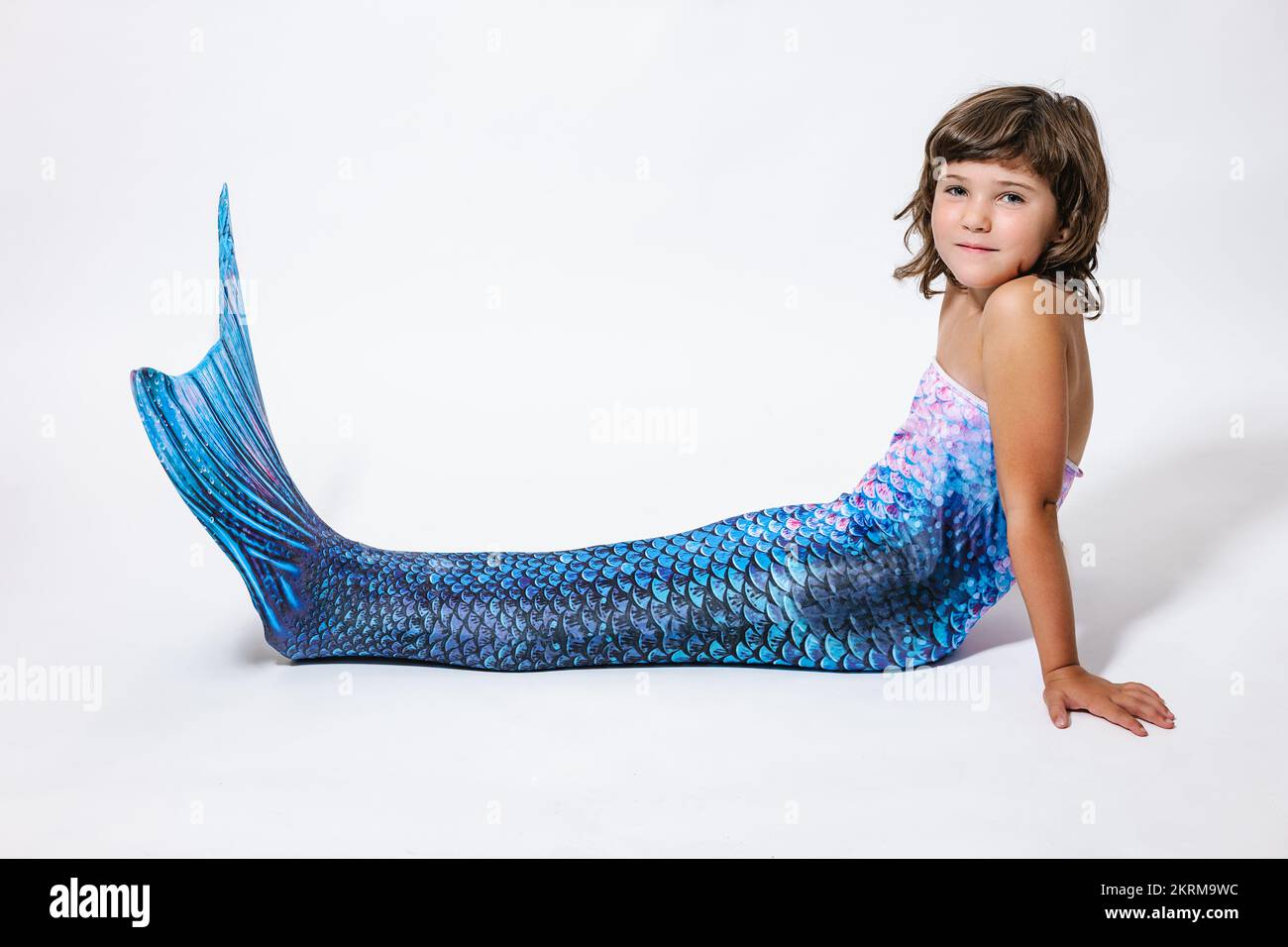Full body of kid wearing blue mermaids tail looking at camera and ...