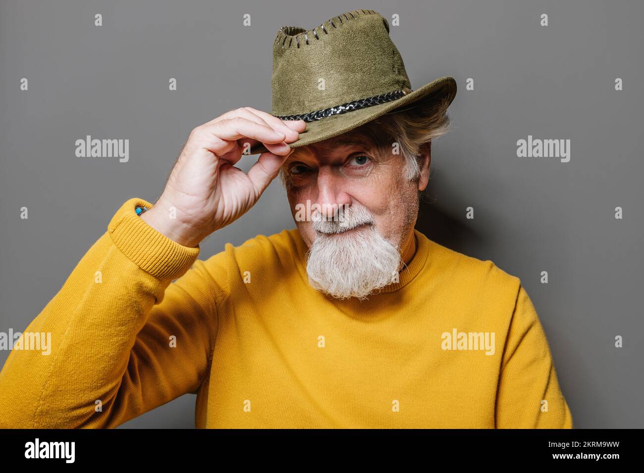 Portrait of gray haired aged male with wrinkles in green cowboy hat and ...