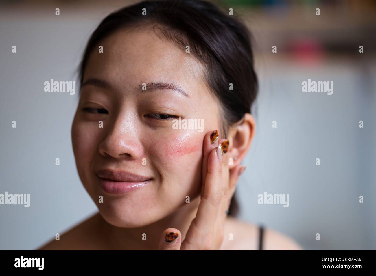 Crop young ethnic female covering cheeks with cream blush while putting ...