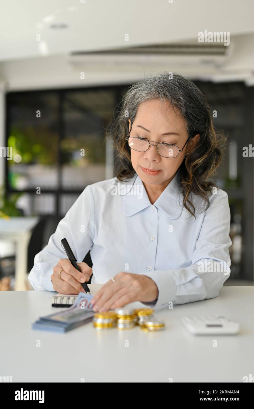 Portrait, Professional Asian aged female accountant using calculator ...