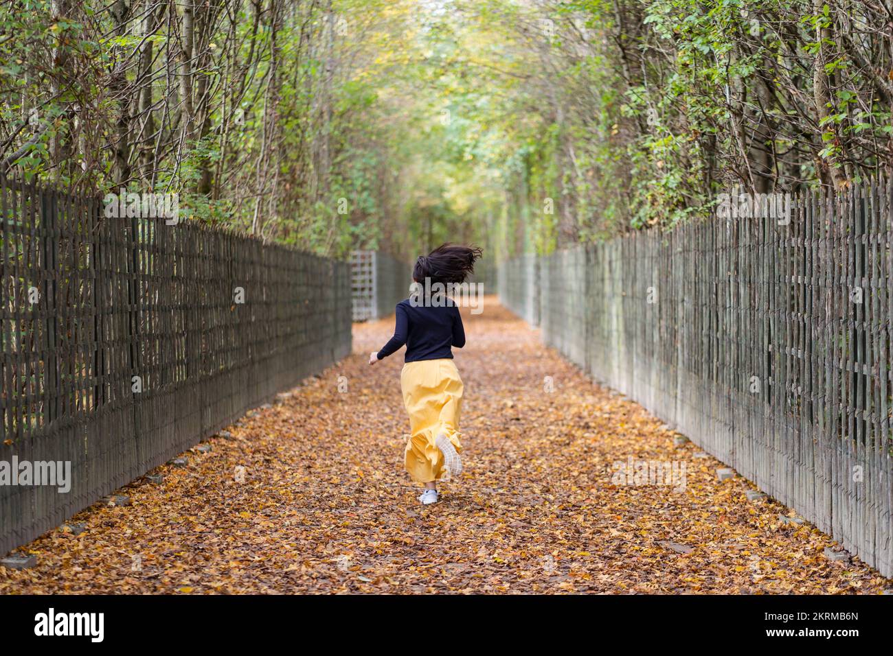 Back view full body of female in long skirt running on walkway with ...
