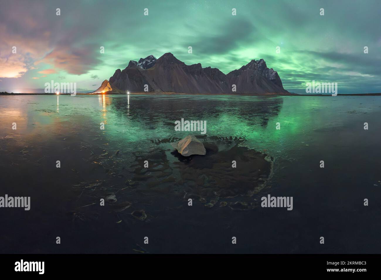 Breathtaking polar light shining over rough stony formation near icy ...