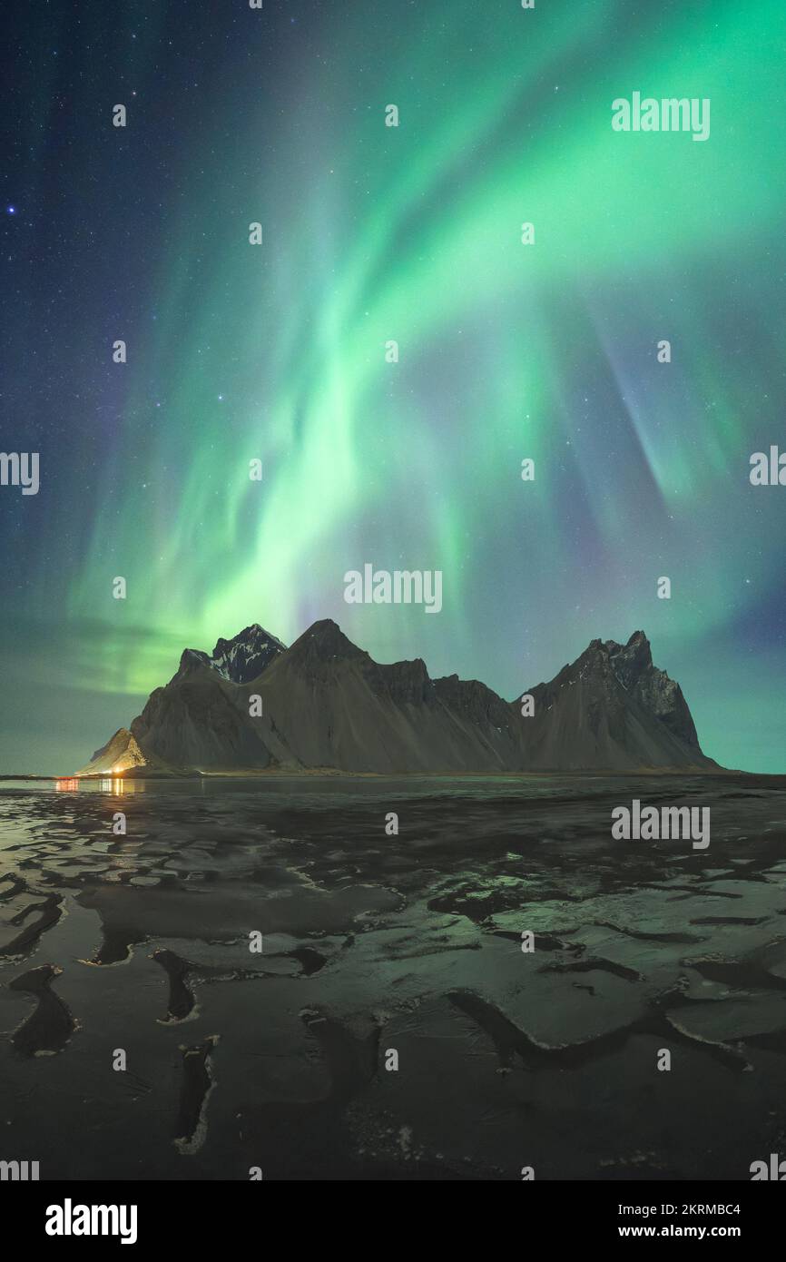 Breathtaking polar light shining over rough stony formation near icy ...