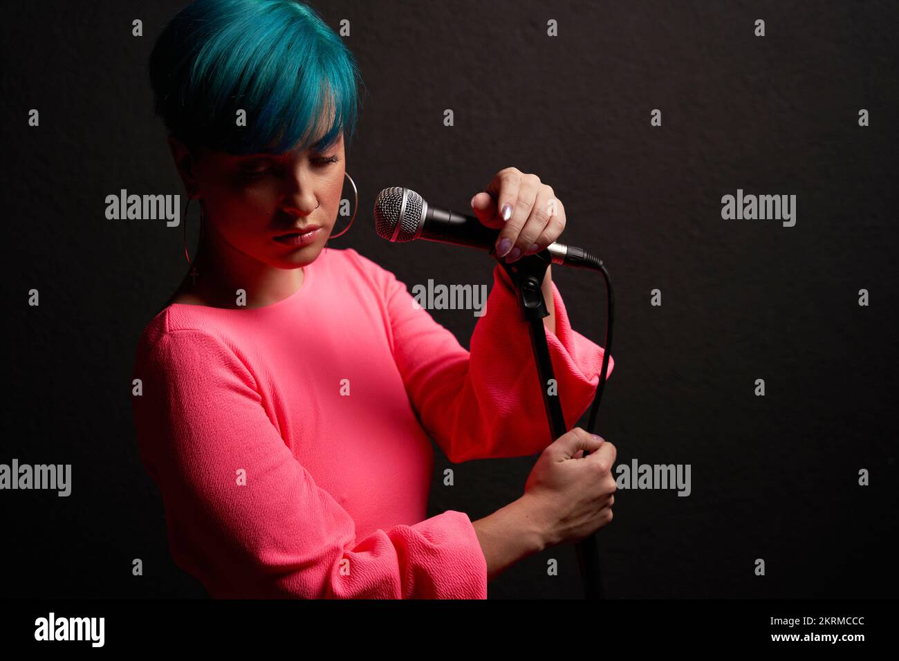Side view of young female in casual clothes holding microphone while ...