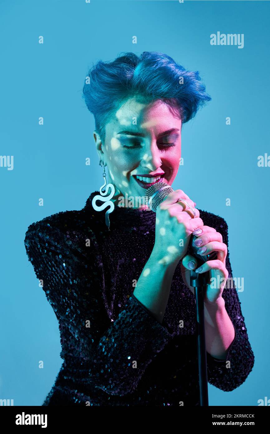 Side view positive young female singer with eyes closed in casual ...