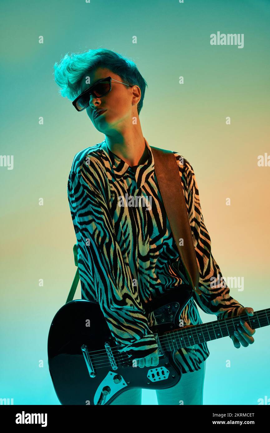 Female musician in trendy outfit and sunglasses playing electric guitar ...