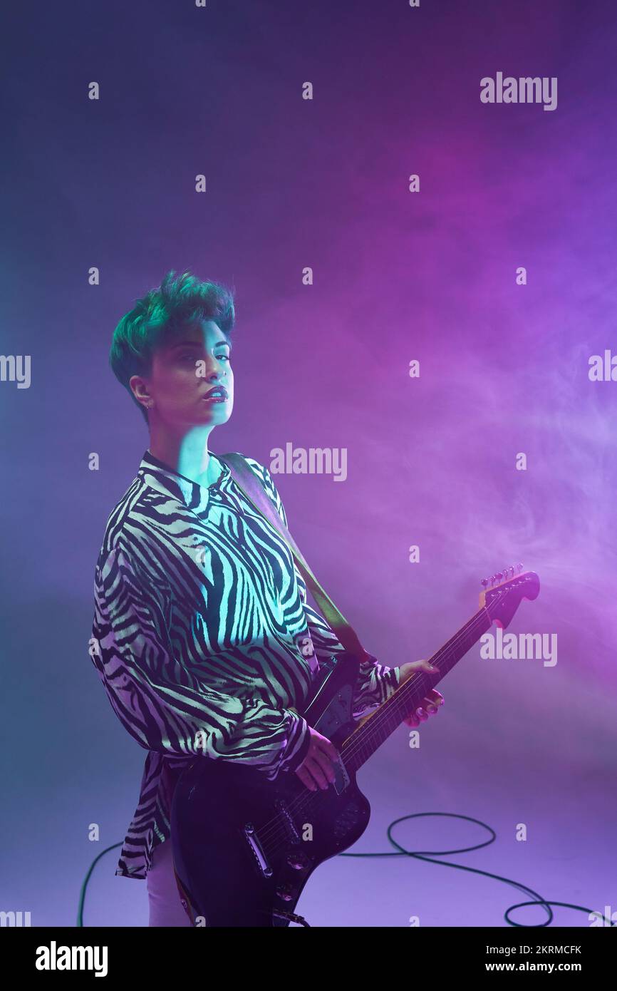 Female musician in trendy outfit playing electric guitar while standing ...