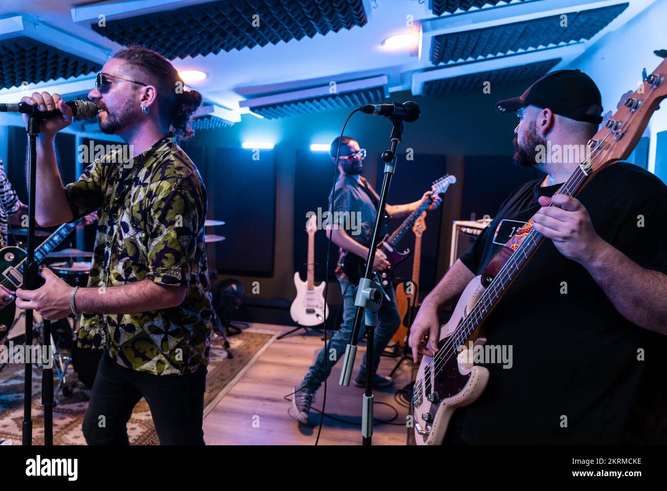 Group of musicians rehearsing song playing electric guitars and drums ...