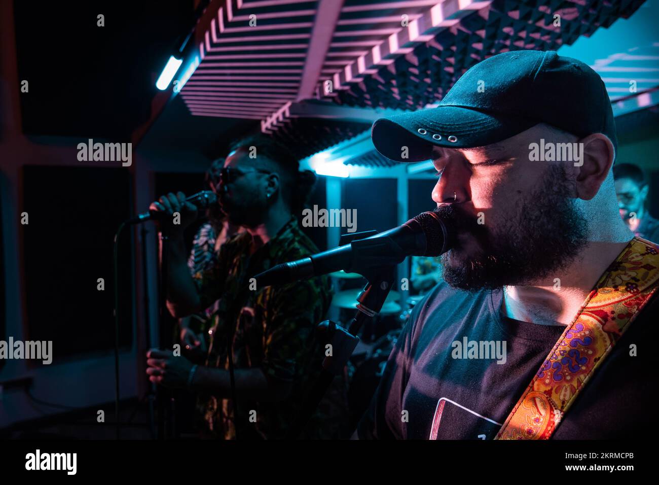 Band singing song into microphones while playing electric guitars ...