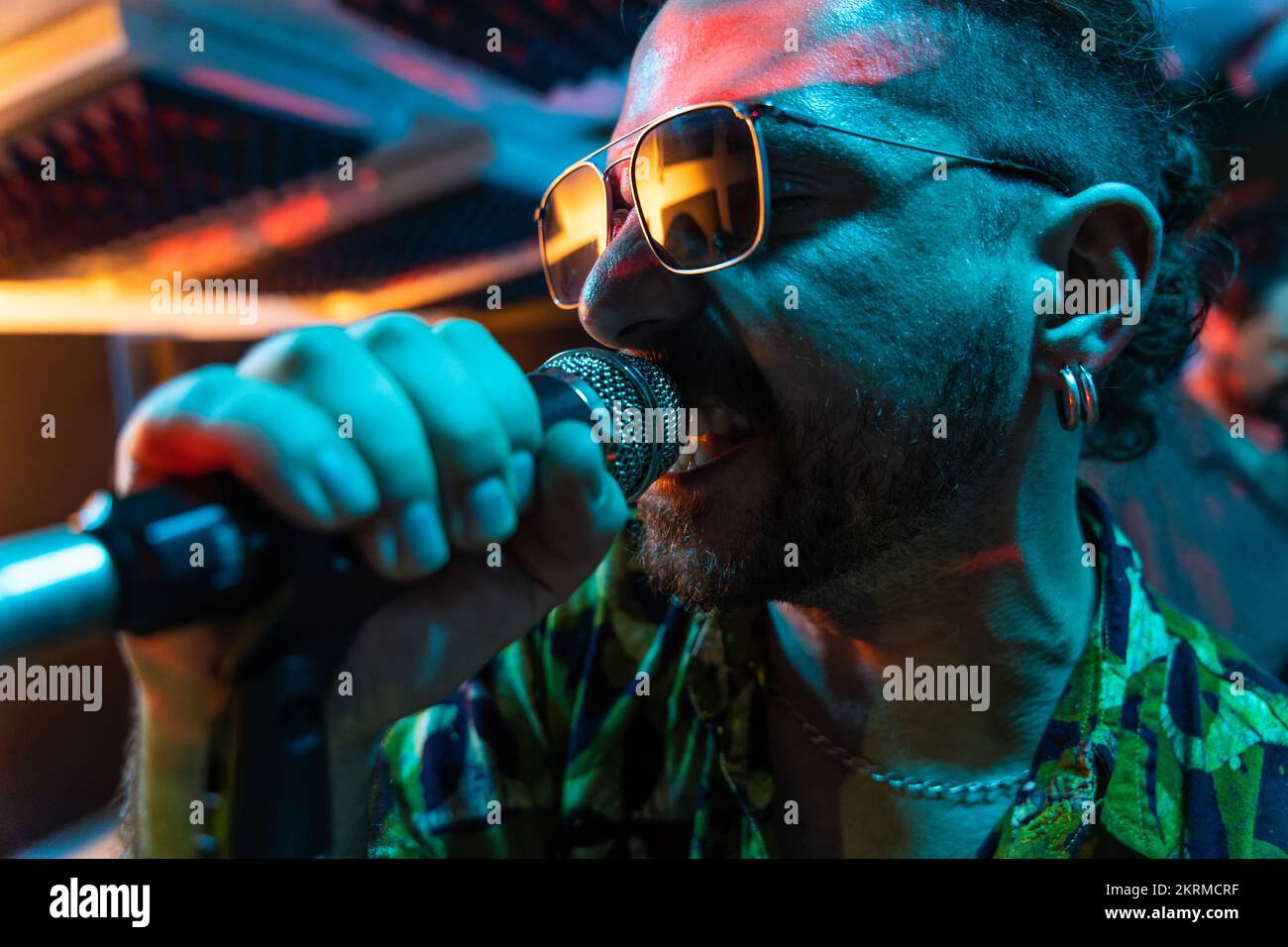 Bearded male singer in stylish shirt with earrings standing in modern ...