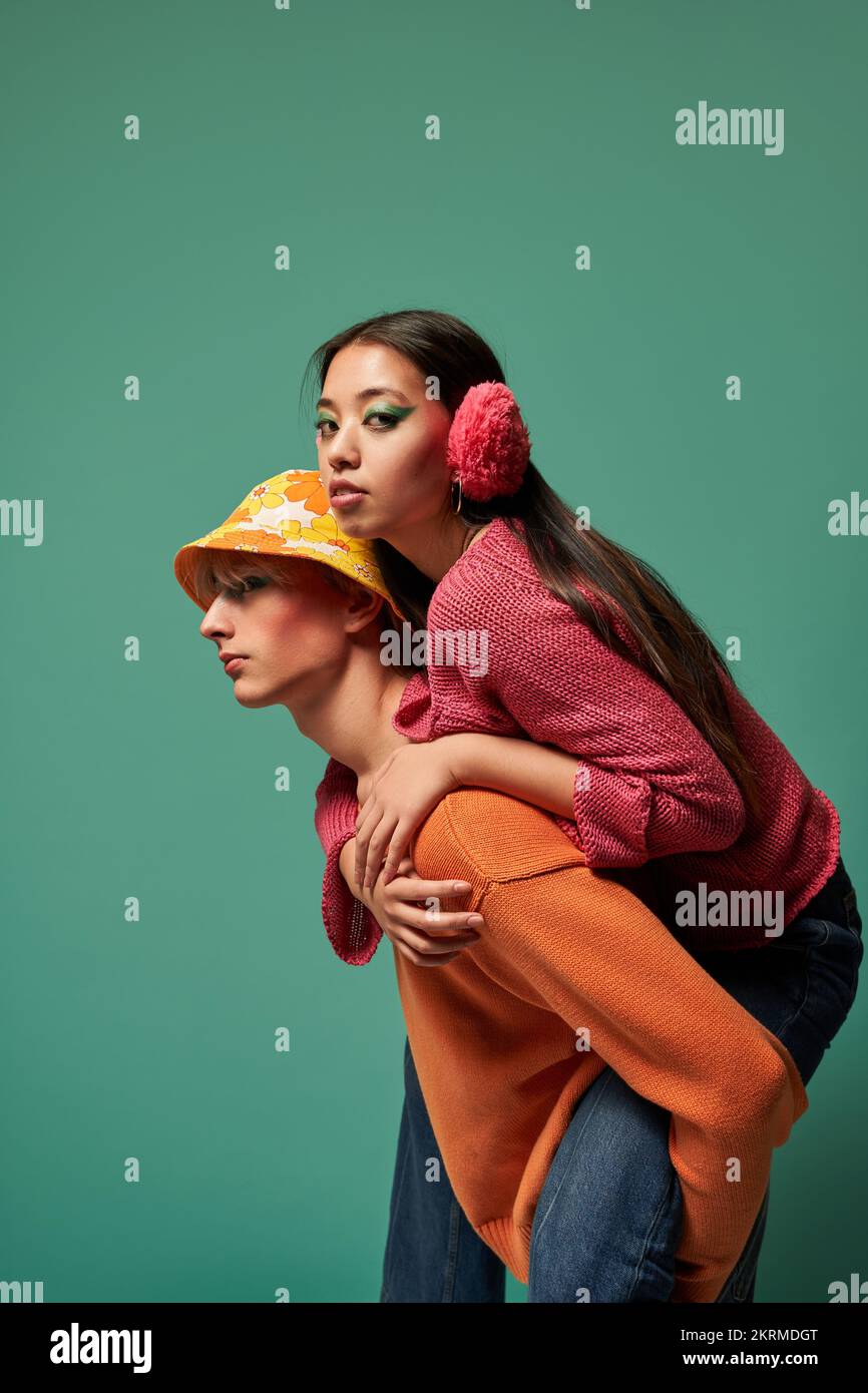 Side view of genderqueer model in colorful stylish clothes carrying ...