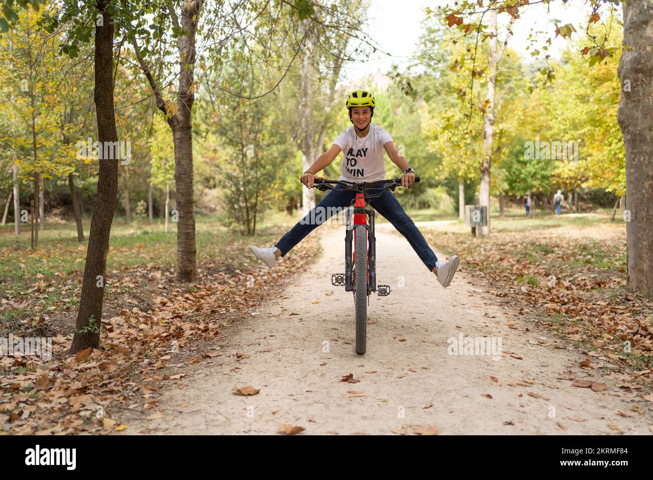 Full body of energetic boy in yellow helmet jumping while riding ...