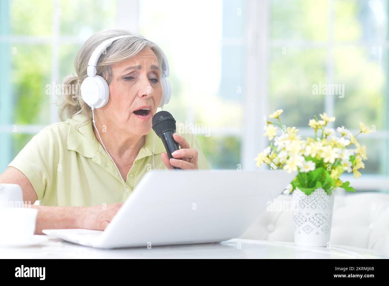 Beautiful senior woman singing karaoke with laptop Stock Photo - Alamy