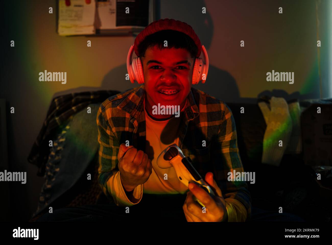 Middle-eastern teenage boy using headphones and controller while ...