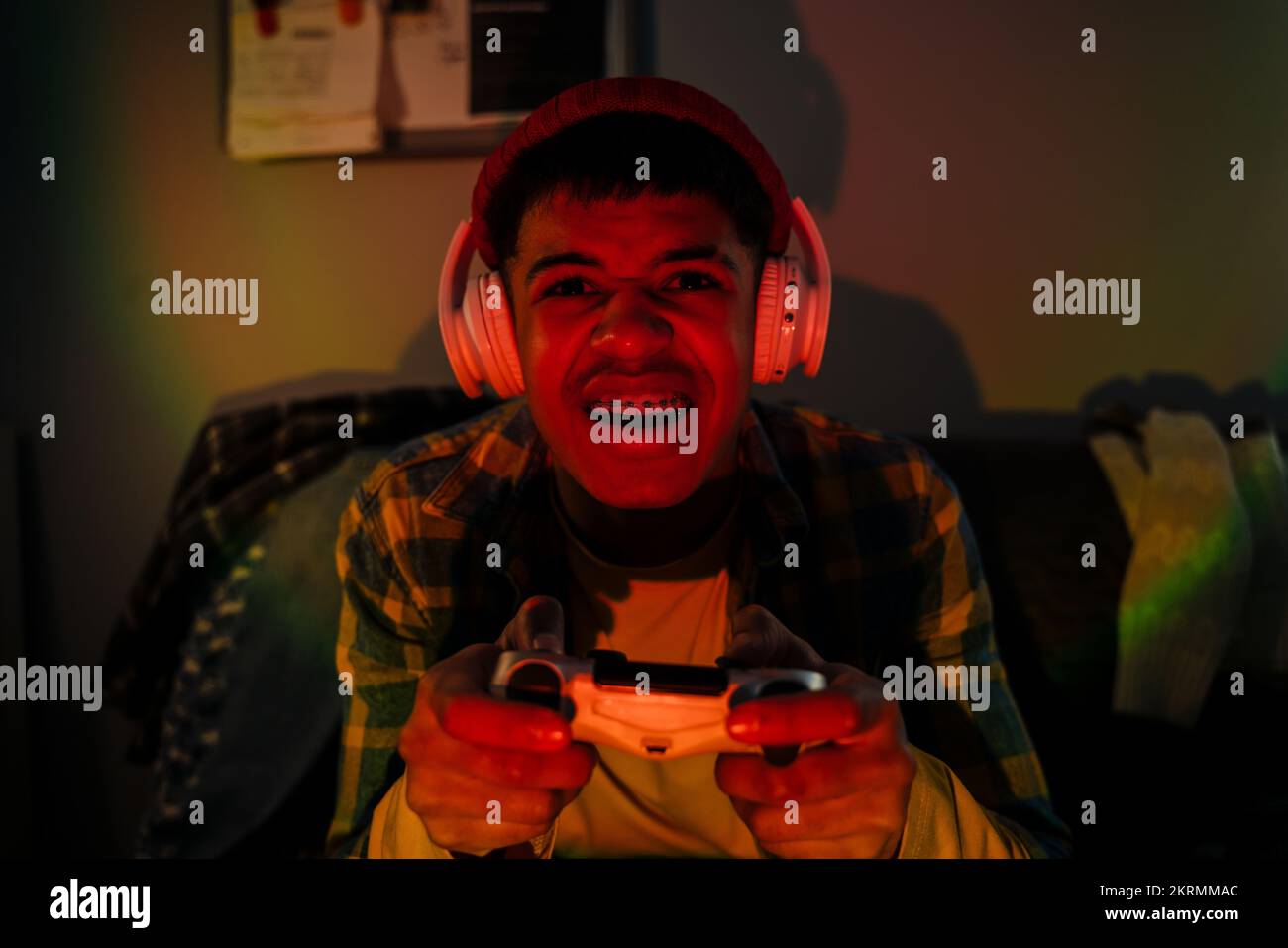 Middle-eastern teenage boy using headphones and controller while ...