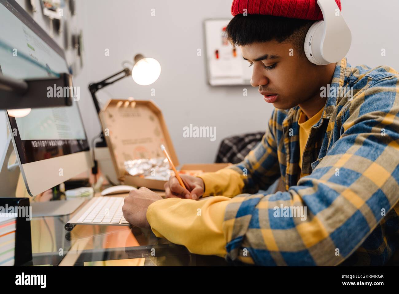 Middle-eastern teenage boy using desktop computer while studying at ...