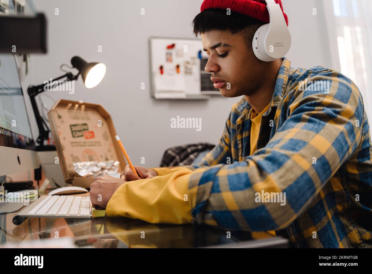 Middle-eastern teenage boy using desktop computer while studying at ...