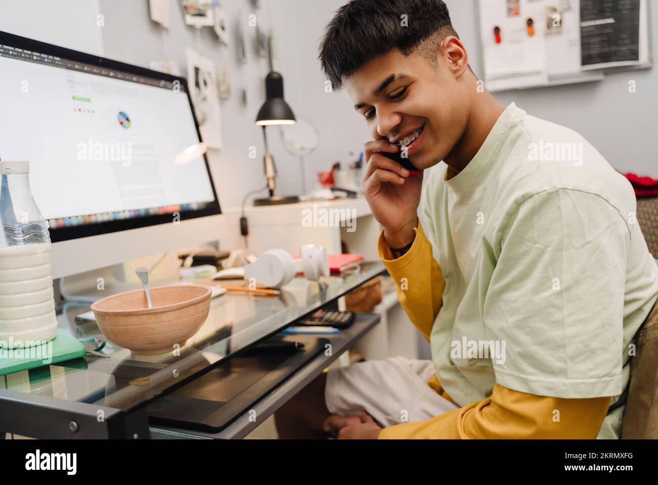 Brunette teenage boy talking on cellphone while having breakfast in ...