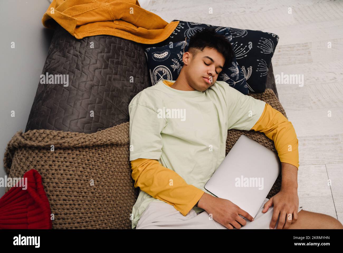 Brunette teenage boy sleeping while lying on couch with laptop in ...