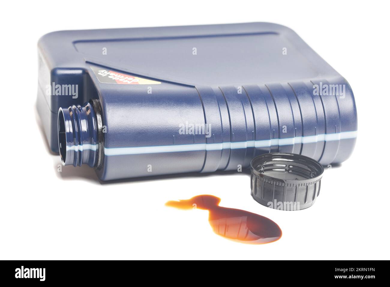 open engine oil bottle with a puddle of engine oil isolated on white ...